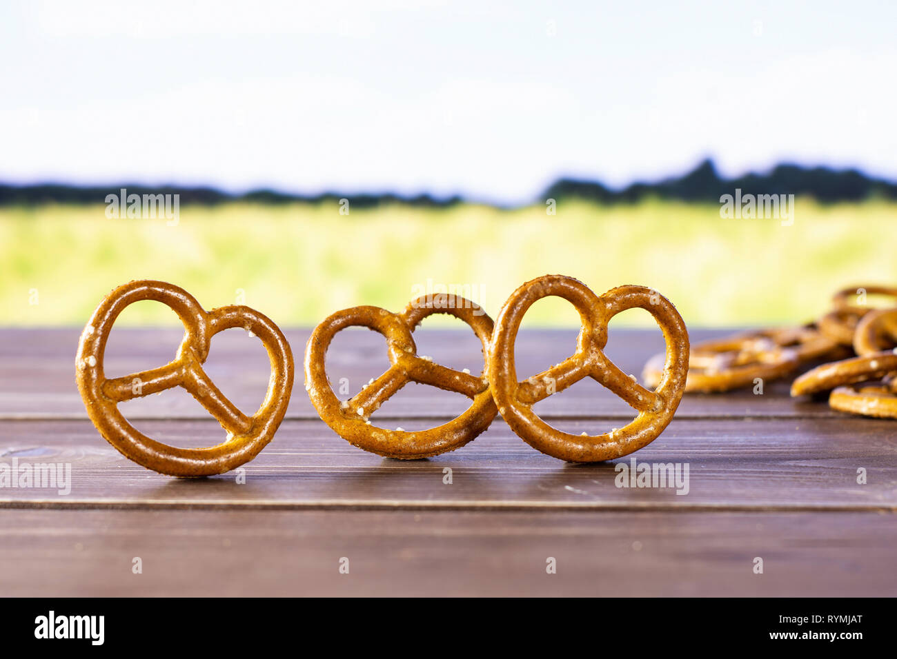 Group of three whole mini salted pretzels with green wheat field Stock ...