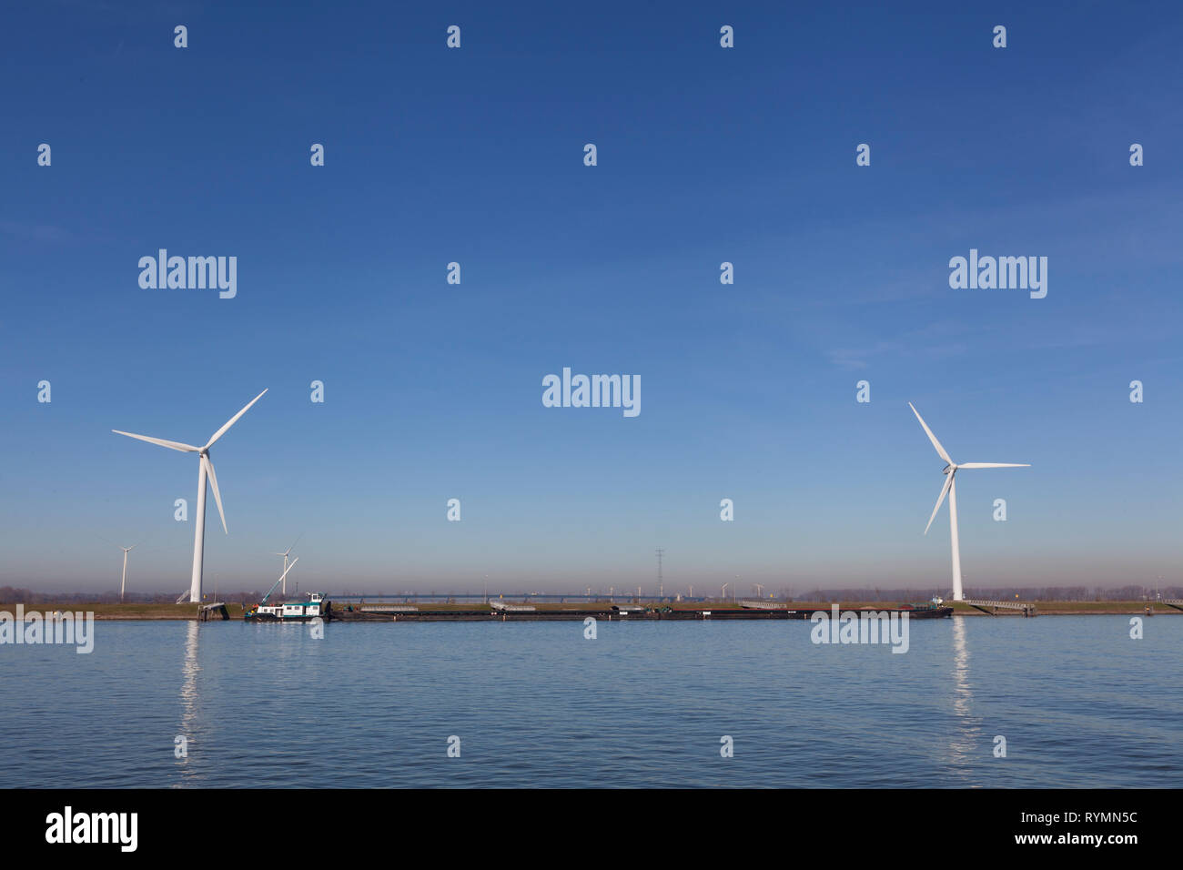 Wind mill, with several wind turbines, near a river, producing green ...