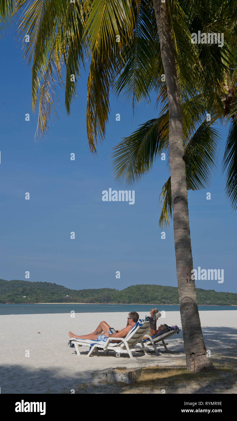 Western tourists reading on a beach in the island of Langkawi,Malaysia ...