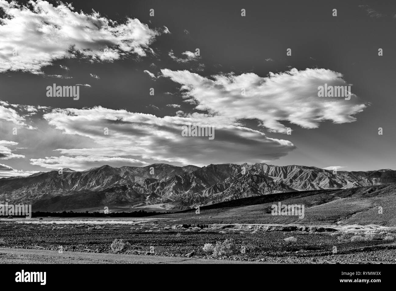 Black and white, barren fields and mountains under desert skies with ...