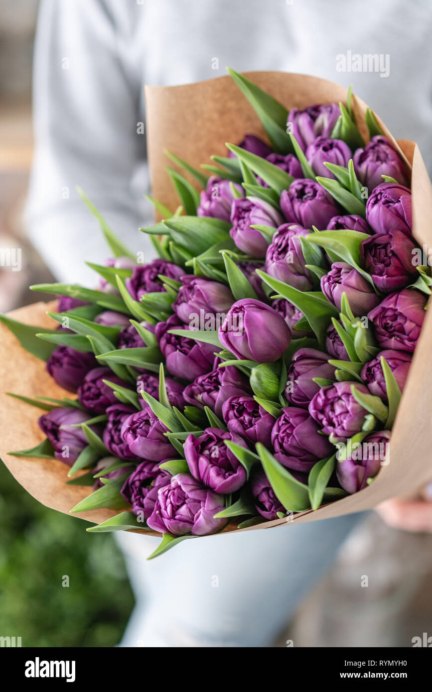 Young beautiful woman holding a spring bouquet of purple tulips in her ...