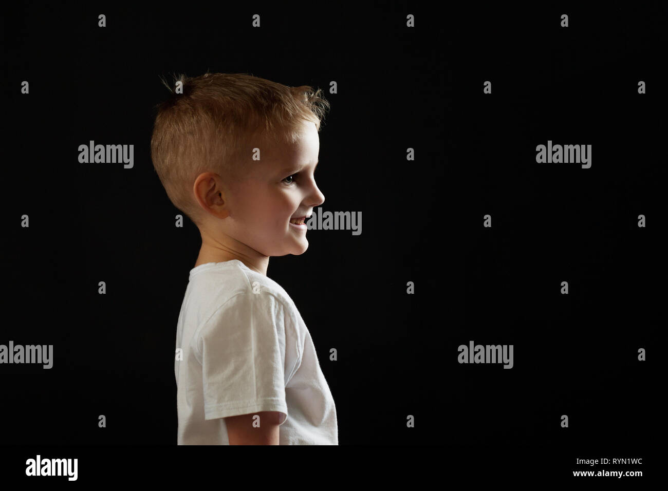 Portrait of a child in profile on a black background. Boy looking ...