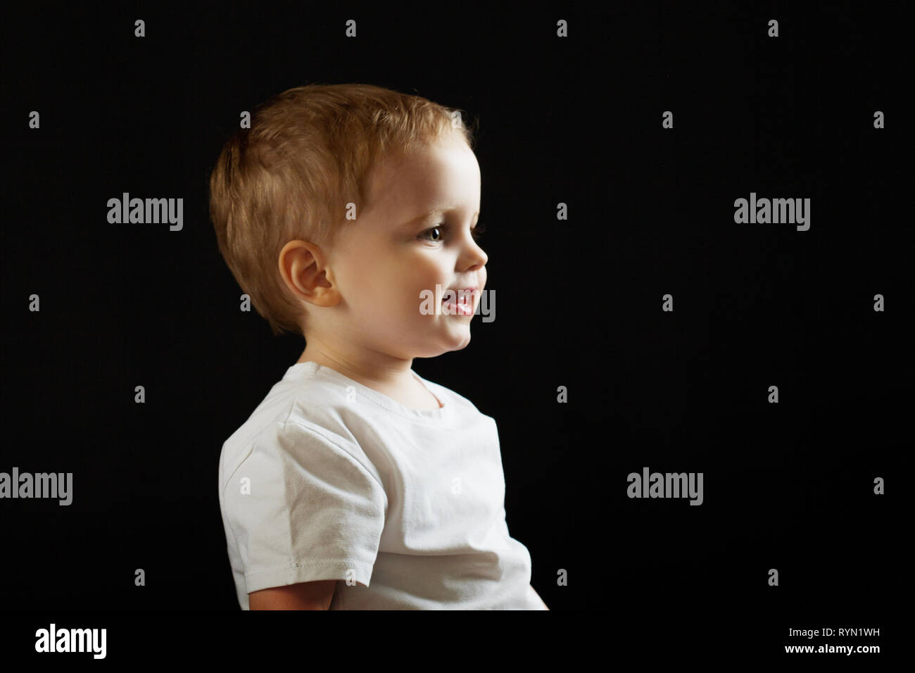 Portrait of a child in profile on a black background. Boy looking ...