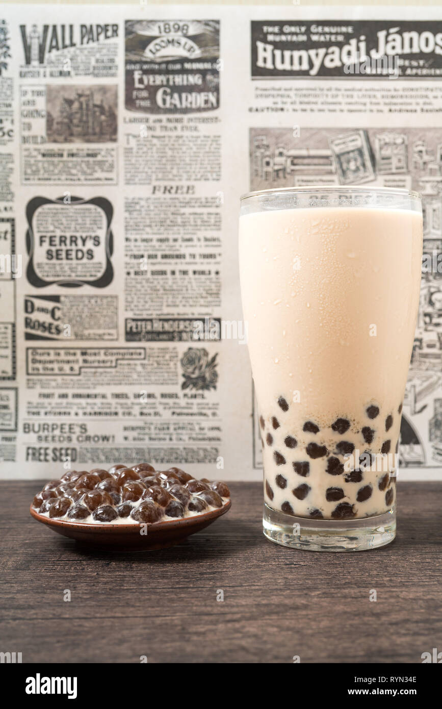 A glass cup of pearl milk tea (also called bubble tea) and a plate of ...