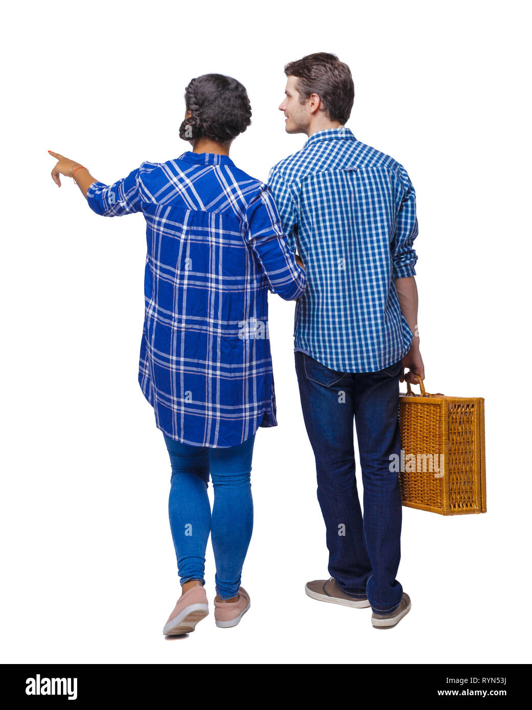 Back view of the interracial couple with a picnic bagwho hugs and ...
