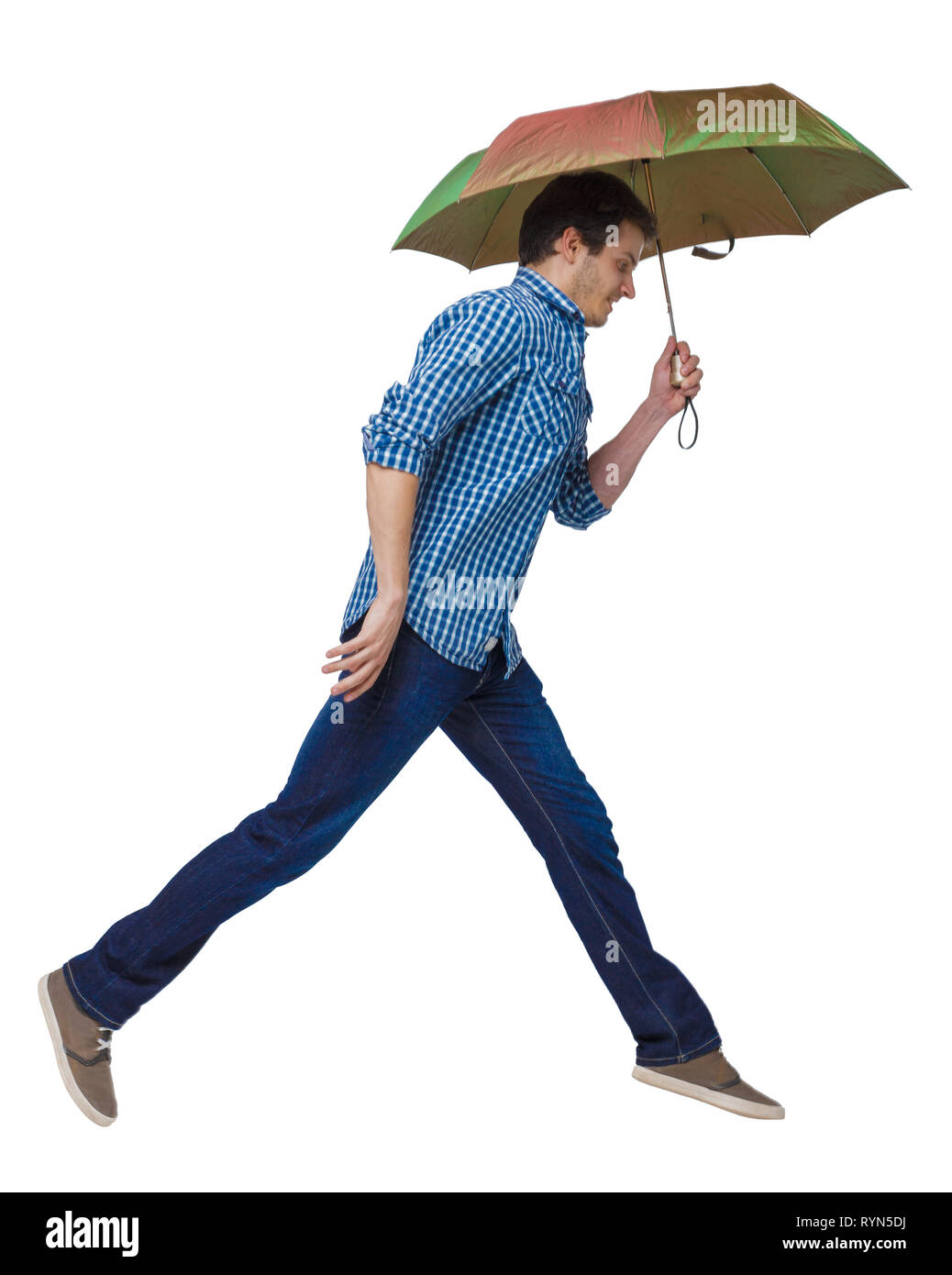 Side view of a man balancing with an umbrella. guy jumps over a puddle ...