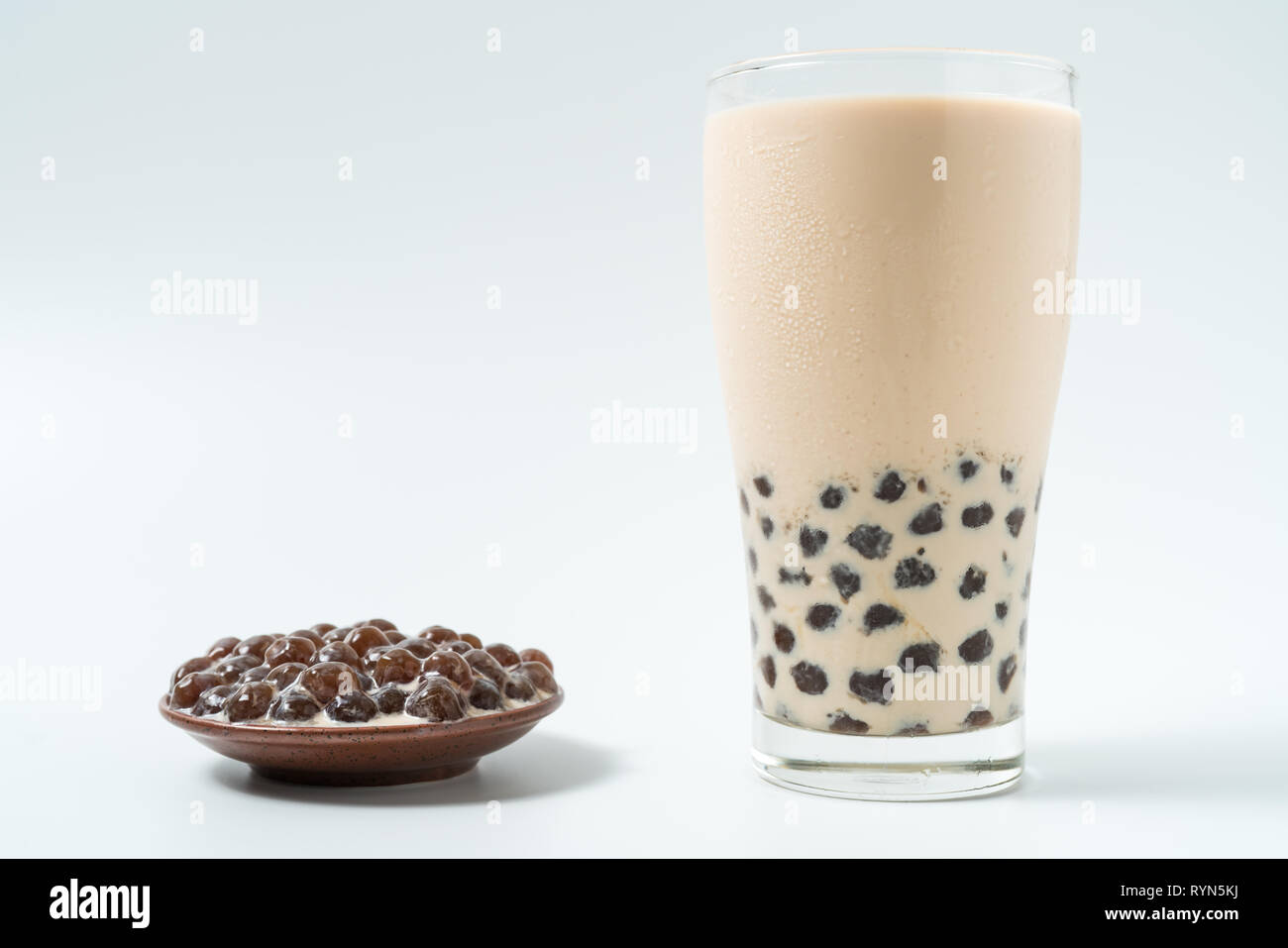 A glass cup of pearl milk tea (also called bubble tea) and a plate of ...