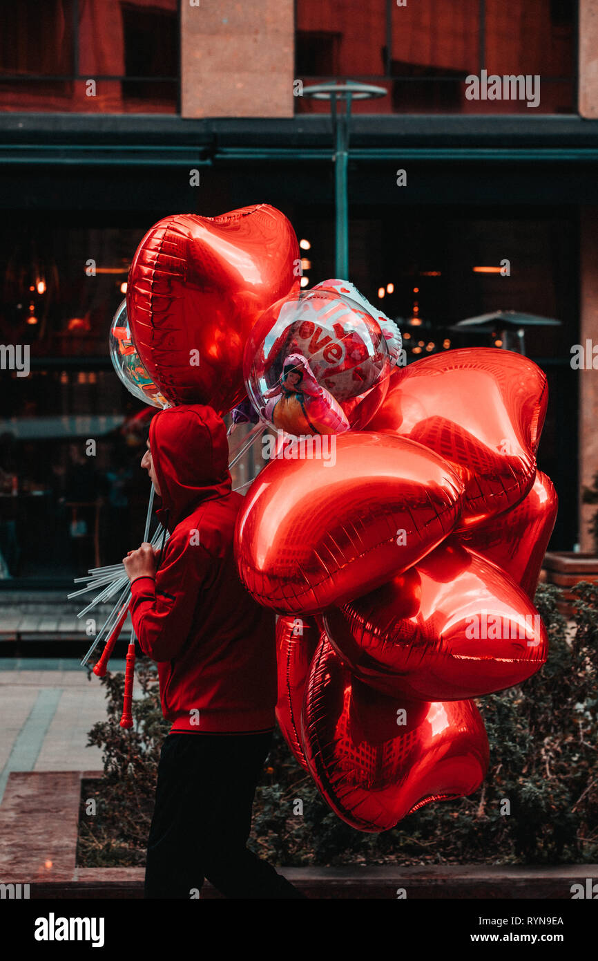 Guy carrying red balloons Stock Photo - Alamy