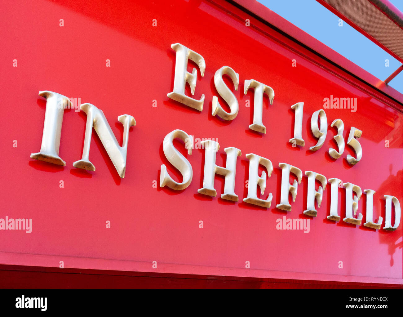 Bright gold letters making a sign on shop front saying Est 1935 in ...