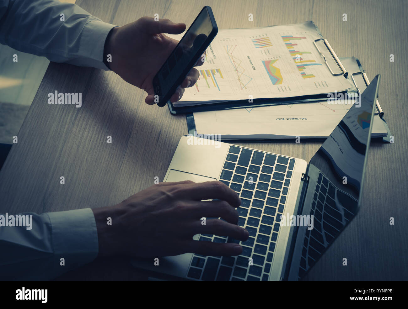 Business man is using computer and mobile on table with financial ...