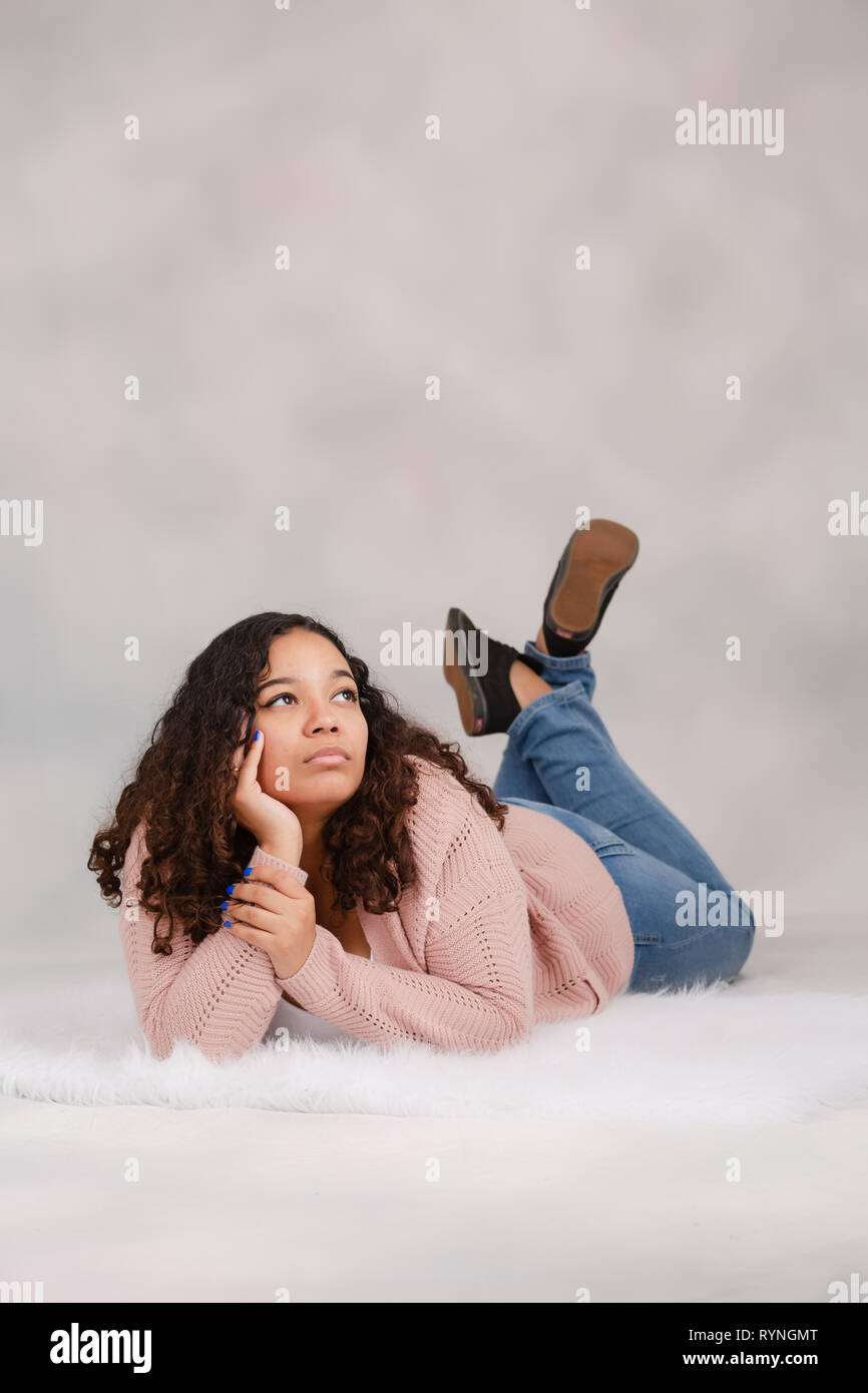 Attractive biracial high school senior laying down on floor posing for ...