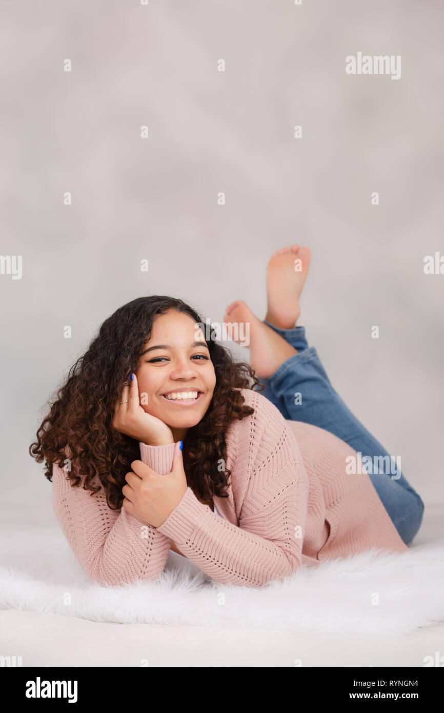 Attractive biracial high school senior laying down on floor smiling and ...