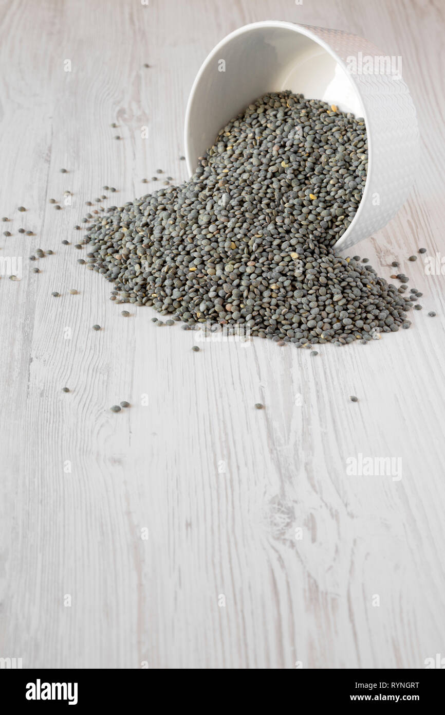 Green french lentils in gray bowl over white wooden surface, side view ...