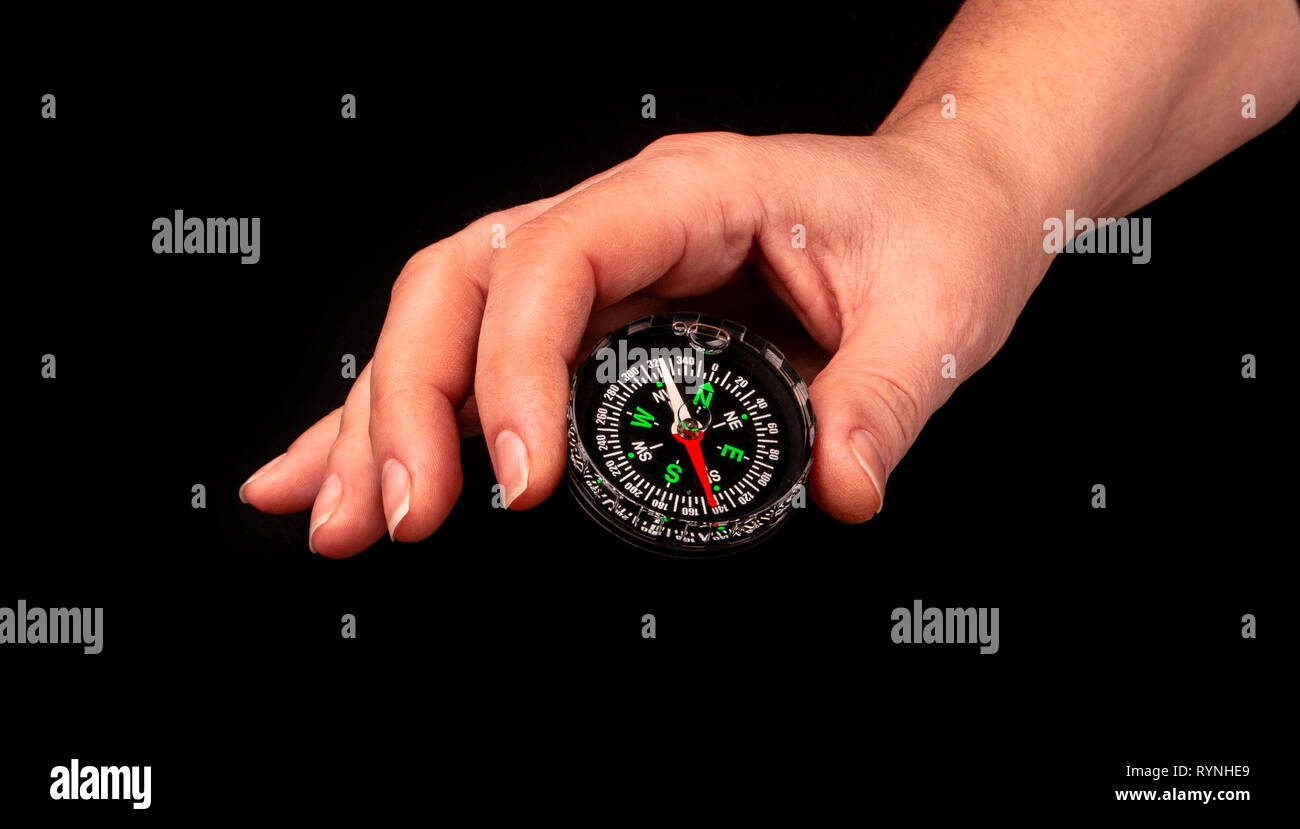 Hand holding the black compass isolated on black background Stock Photo ...