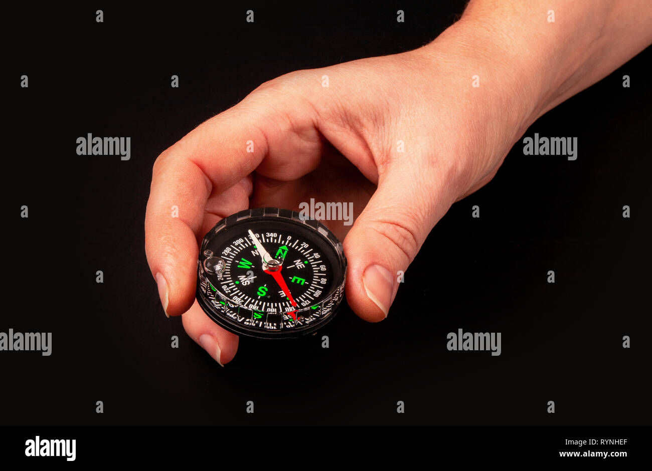 Hand holding the black compass isolated on black background Stock Photo ...