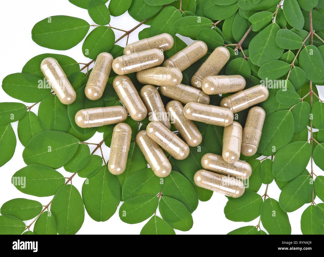 Herbal capsules with leaf on white background Stock Photo - Alamy