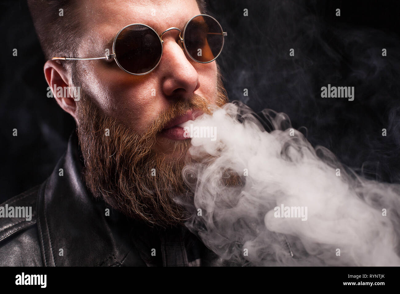 Bearded man in leather jacket and brown sunglasses over black ...
