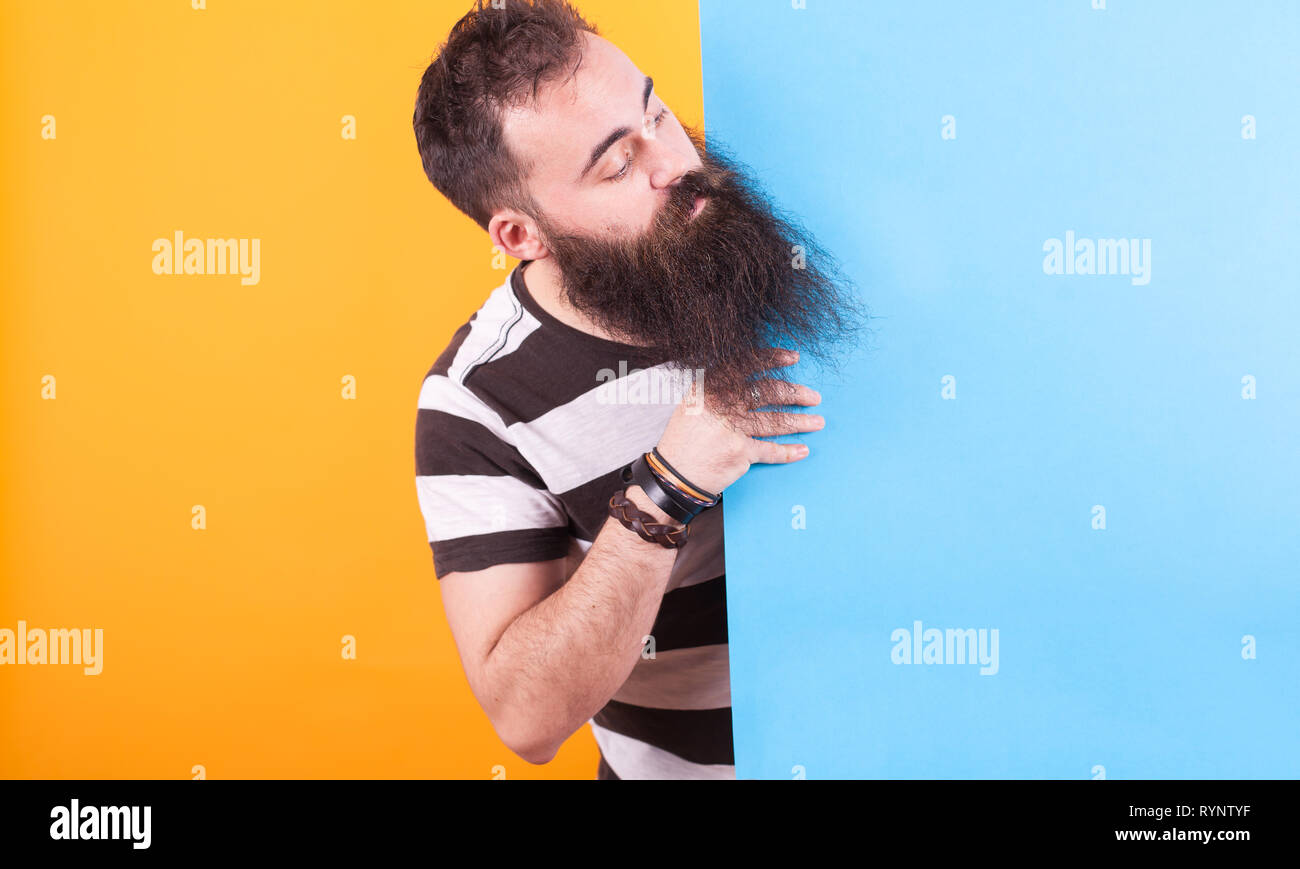 Portrait of bearded man sticking his head out behind a blue pannel over ...