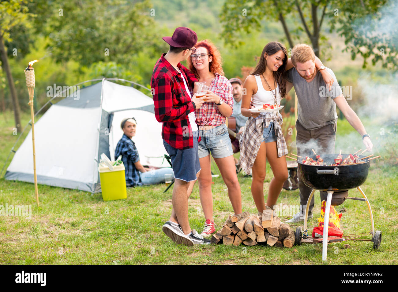 Two young hugging couples in love near barbecue in green nature Stock ...