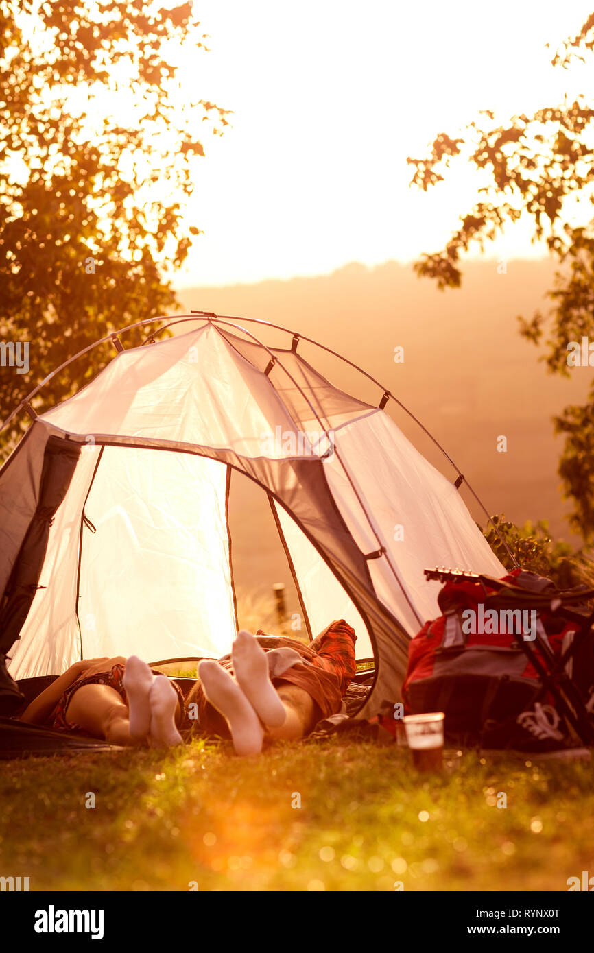 Tired couple lying in tent, relaxing after party on music festival ...