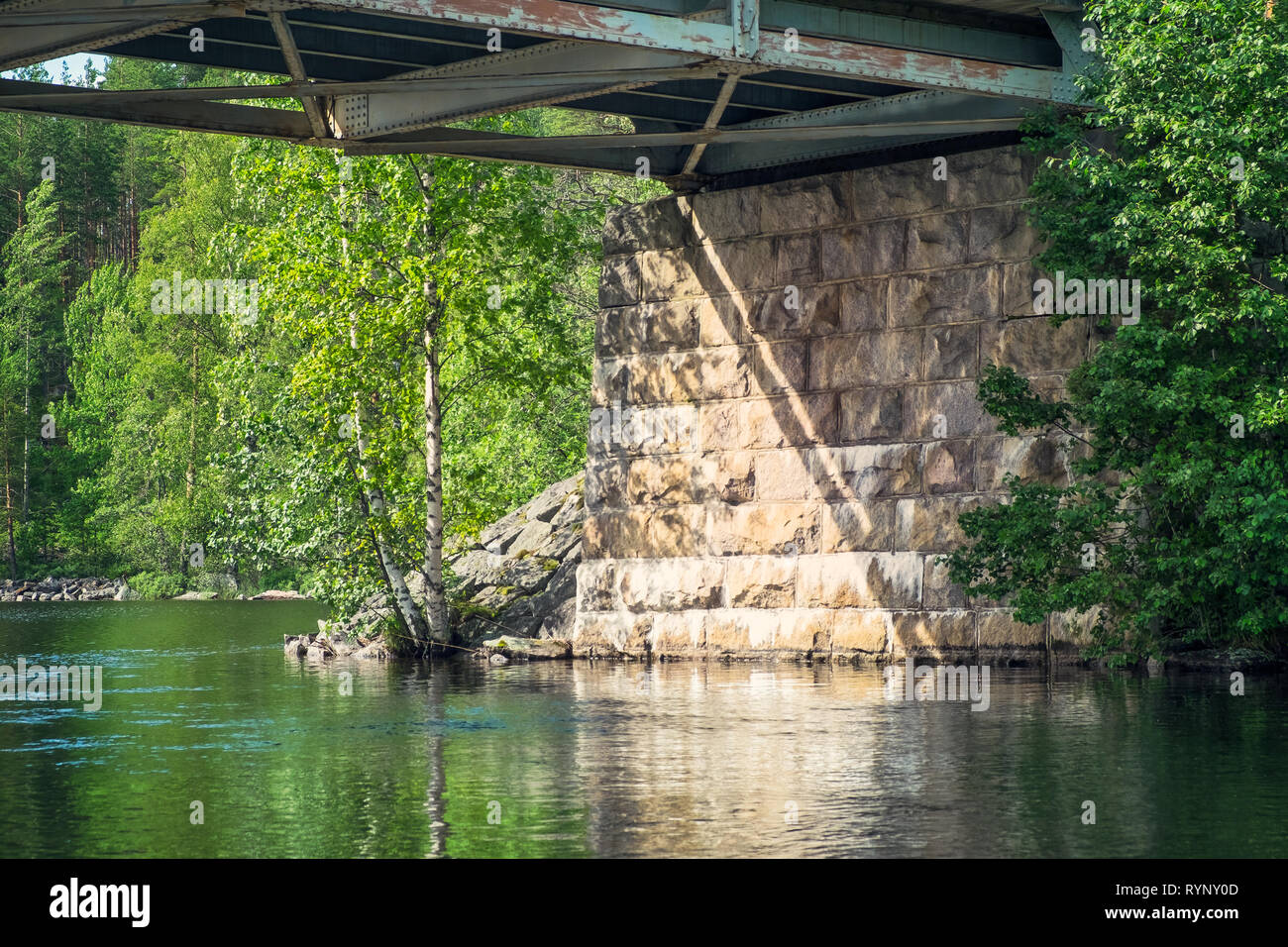 Under bridge landscape with lush foliage trees at summer day in Finland ...