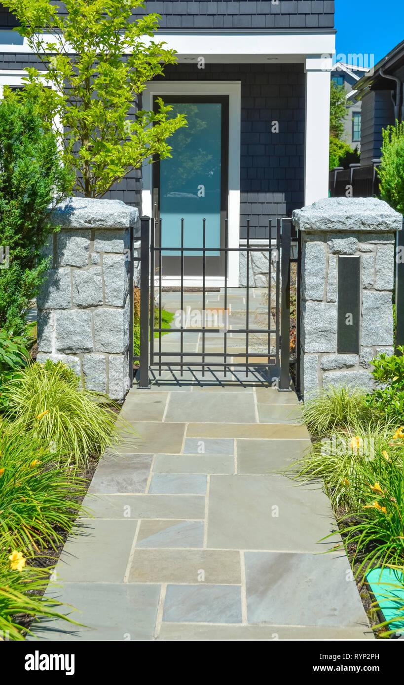 Stone tile paved pathway leading to the entrance door through metal ...