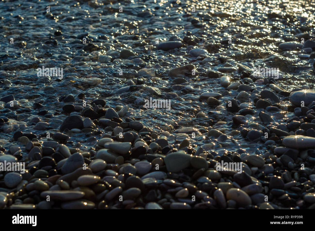 pebble stones on the sea beach, the rolling waves of the sea with foam ...