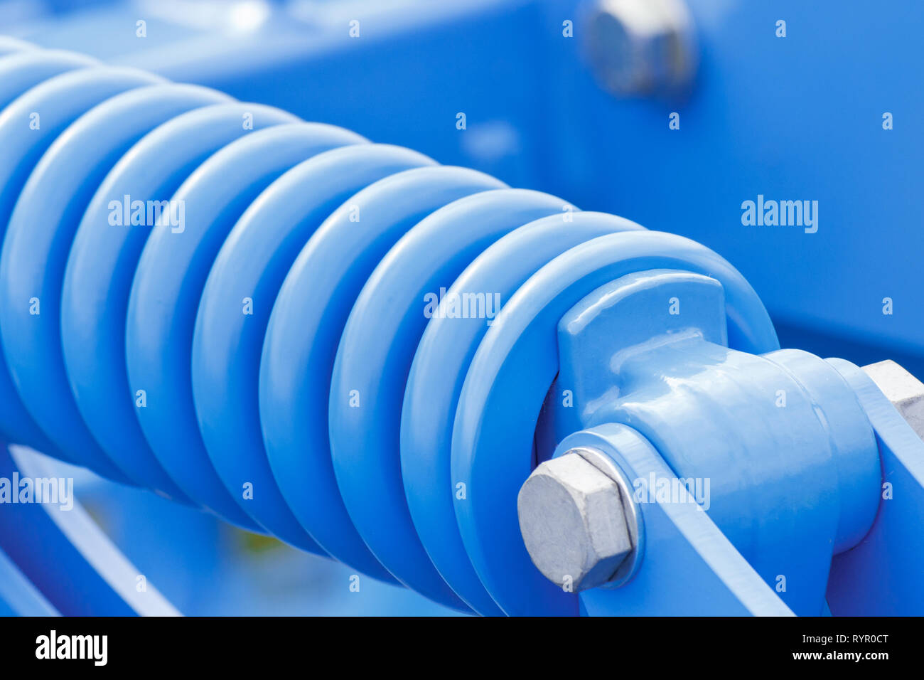 Steel spring as detail of blue industrial or agricultural machinery ...