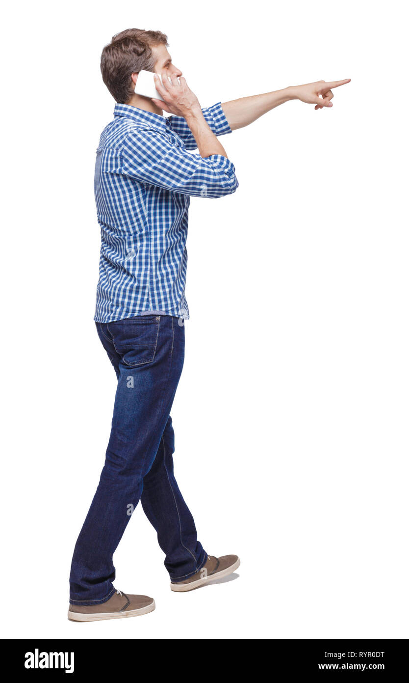 back view of walking man. guy going, pointing and talking on smartphone ...