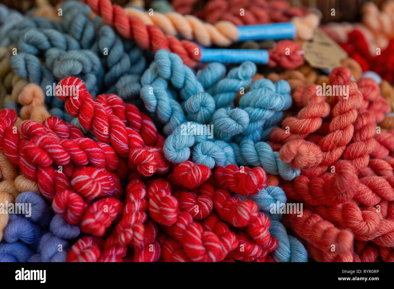 A pile of natural knitting yarn of red, blue and brown colors is ready ...
