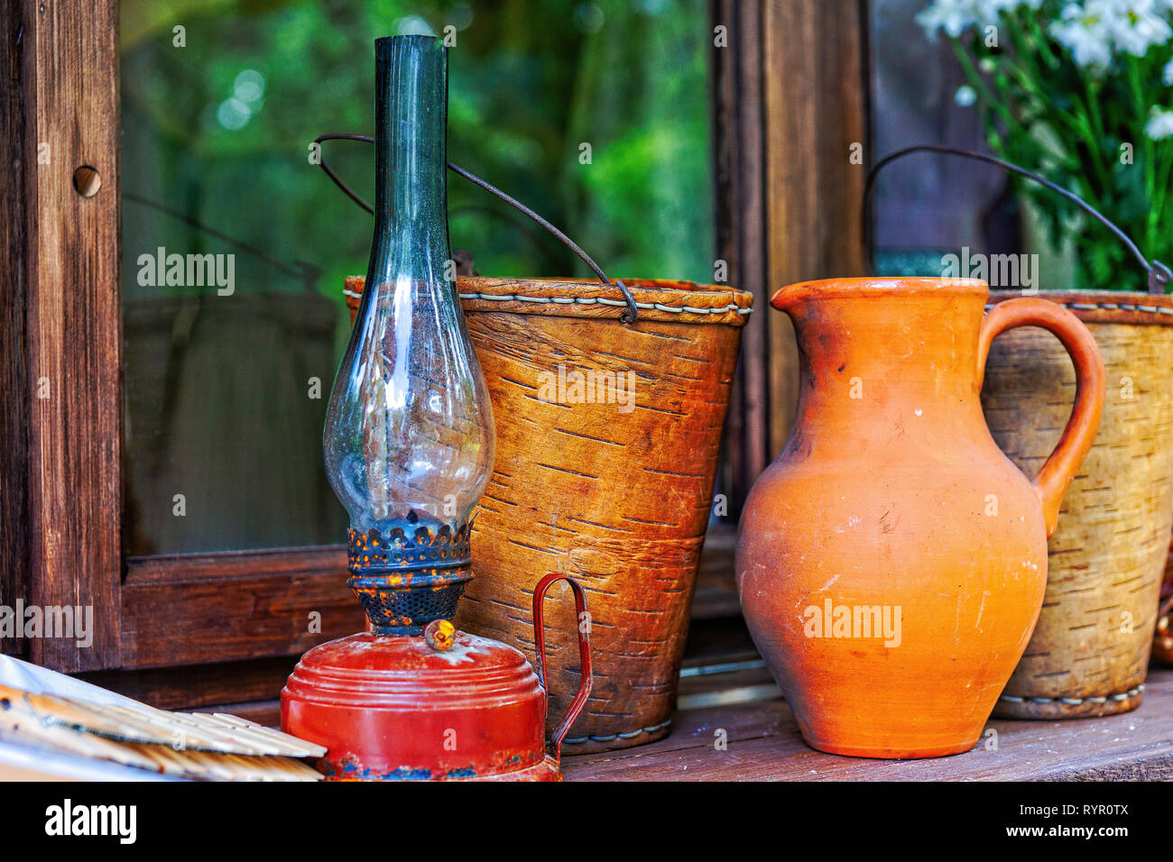 Still-life with a vintage oil lamp, bust bucket, and a ceramic pitcher ...