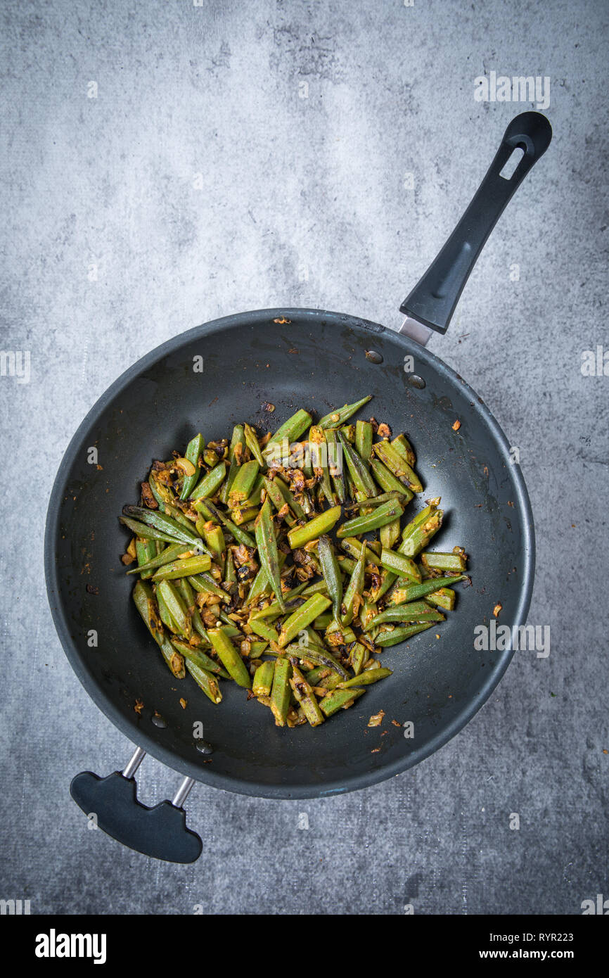 Sliced okra pieces in a wok, fried in Indian spices ready to be served ...