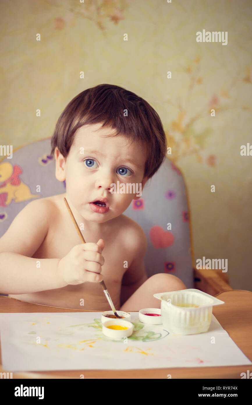 The boy paints on paper. Red and yellow paint. Children's activities ...