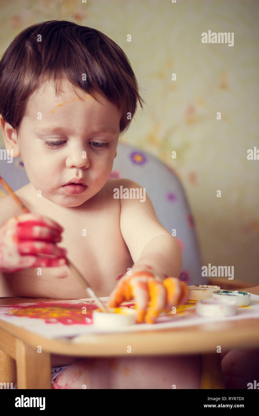 The boy paints on paper. Red and yellow paint. Children's activities ...