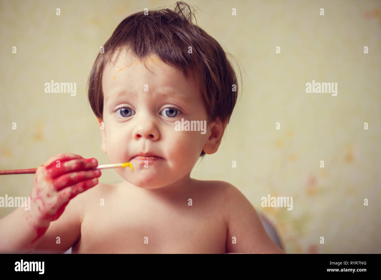 The boy paints on paper. Red and yellow paint. Children's activities ...
