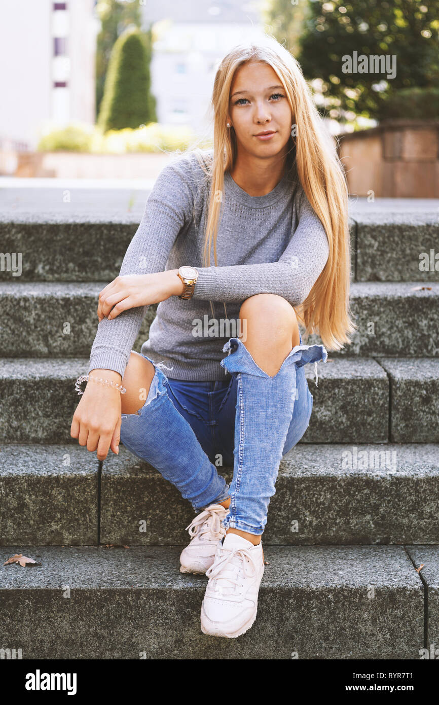 teenage girl sitting on steps outside Stock Photo - Alamy