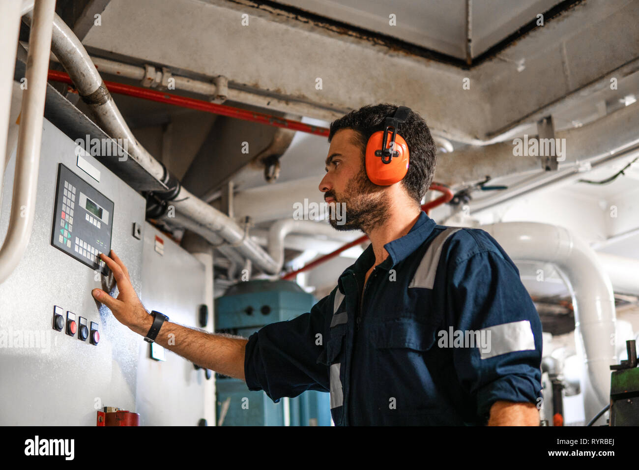 Marine engineer officer working in engine room Stock Photo - Alamy