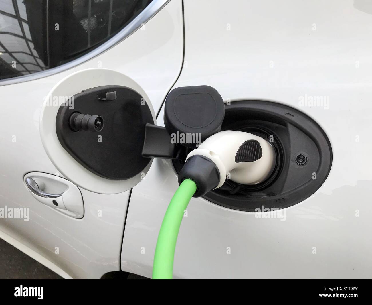 Charging plug on electric car, car being charged at charging station ...