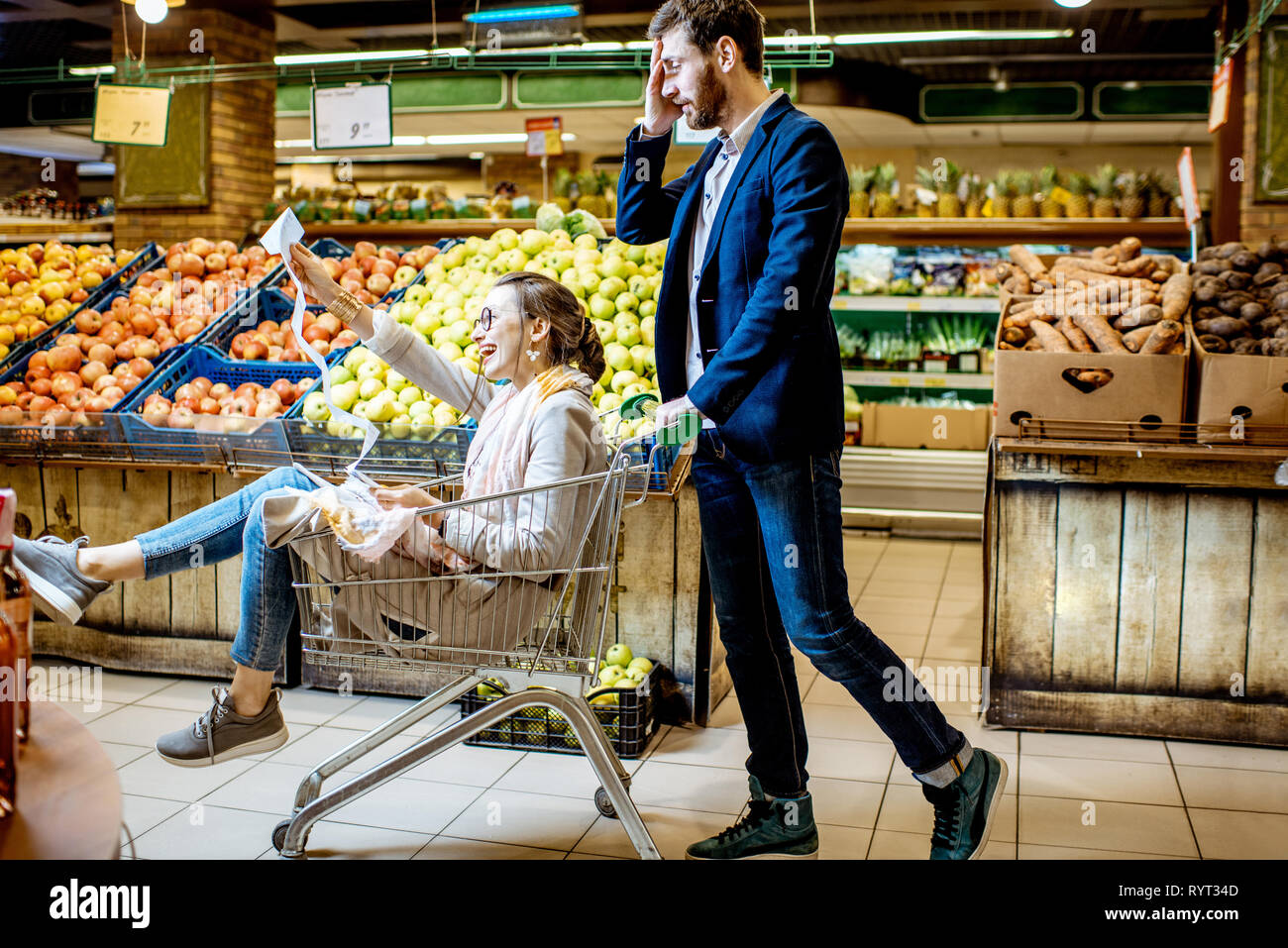 Man and woman having fun while riding in the cart with shopping list in ...