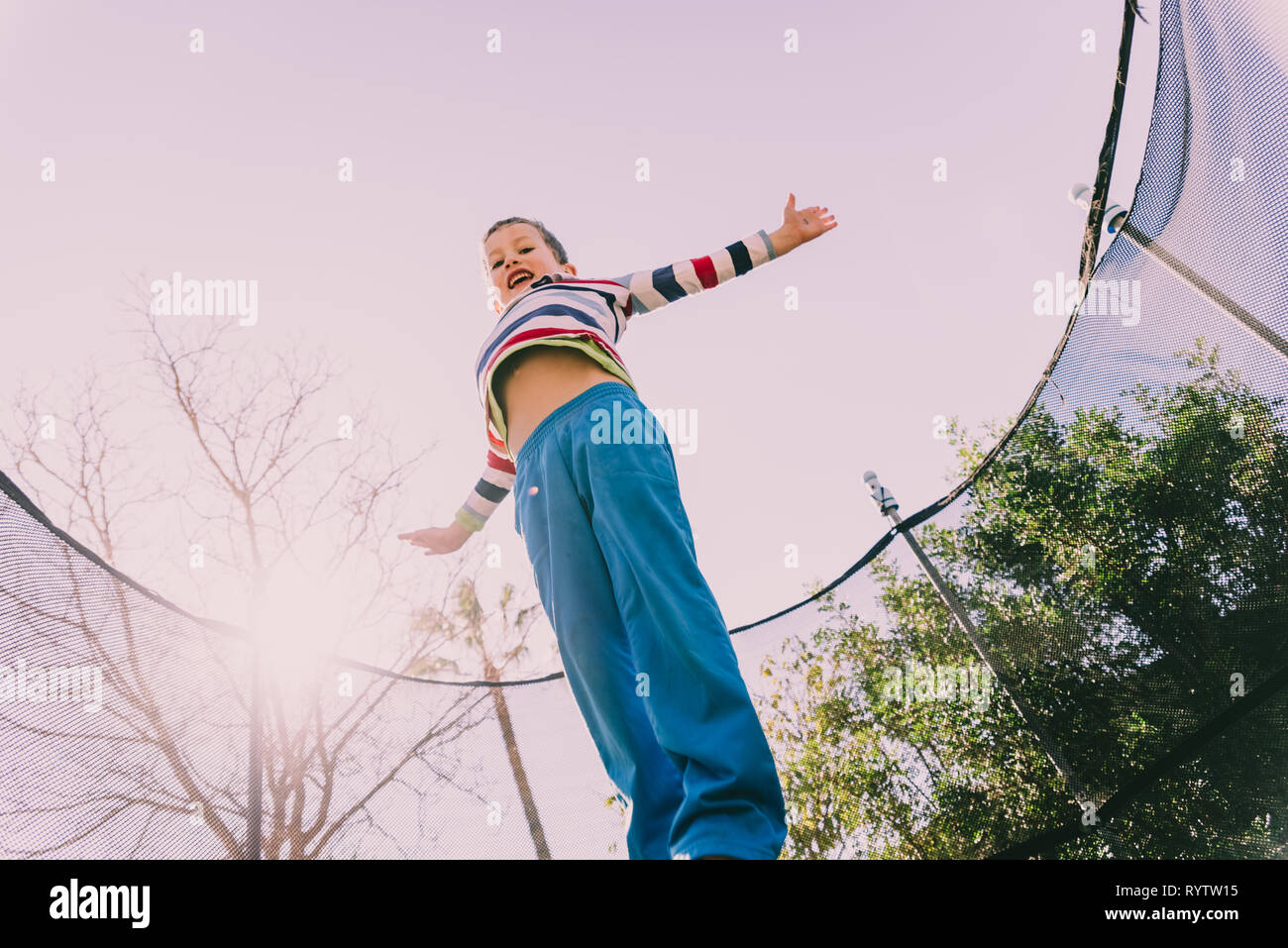 Child exercising in the backyard of his house jumping, casual portrait ...