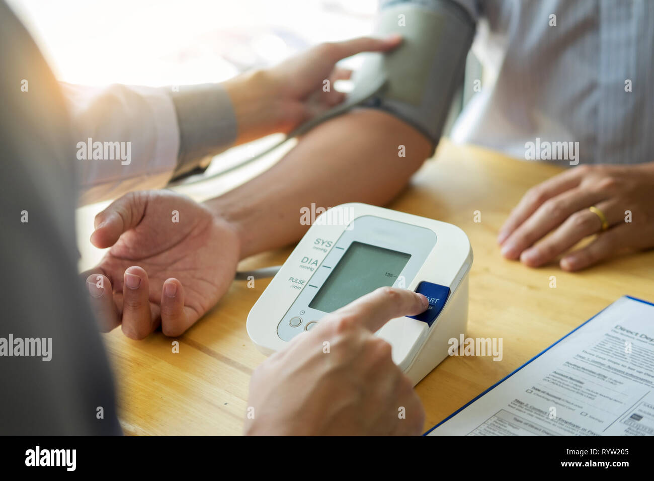 Doctor measuring and checking blood pressure of patient in hospital ...