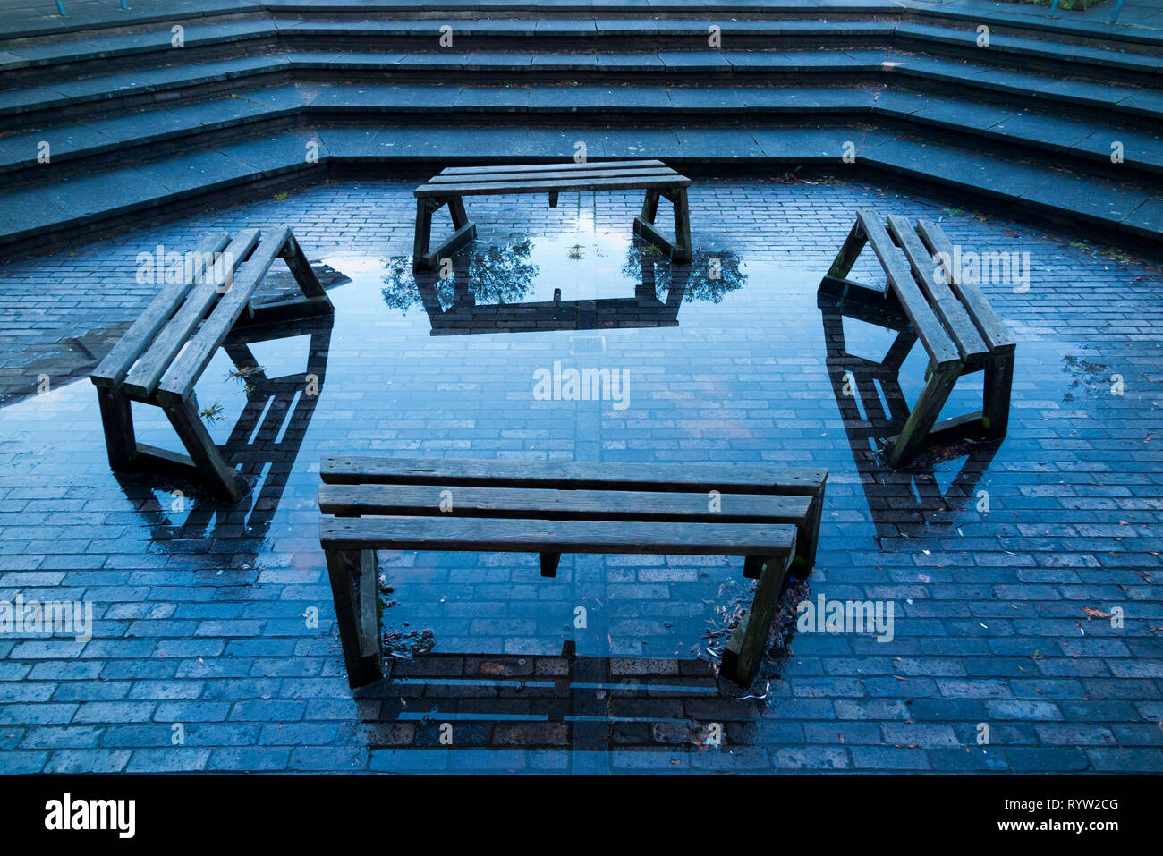 Empty bench seat / seats / benches / chair / chairs sitting in a puddle ...