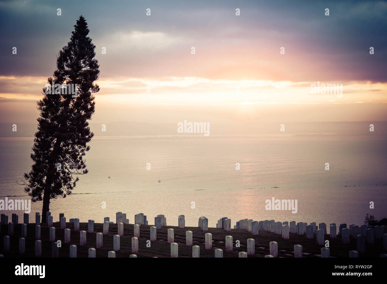 The sun rising over an ocean with a national cemetery in the foreground ...