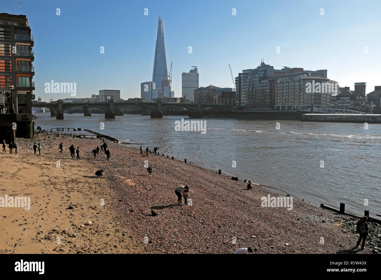 View of River Thames at low tide, Shard building, people mudlarking ...
