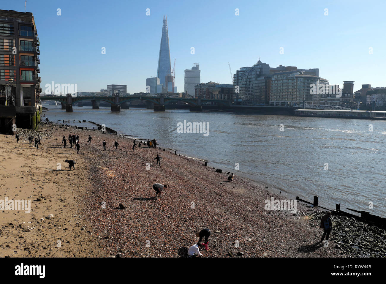 View of River Thames at low tide, Shard building, people mudlarking ...