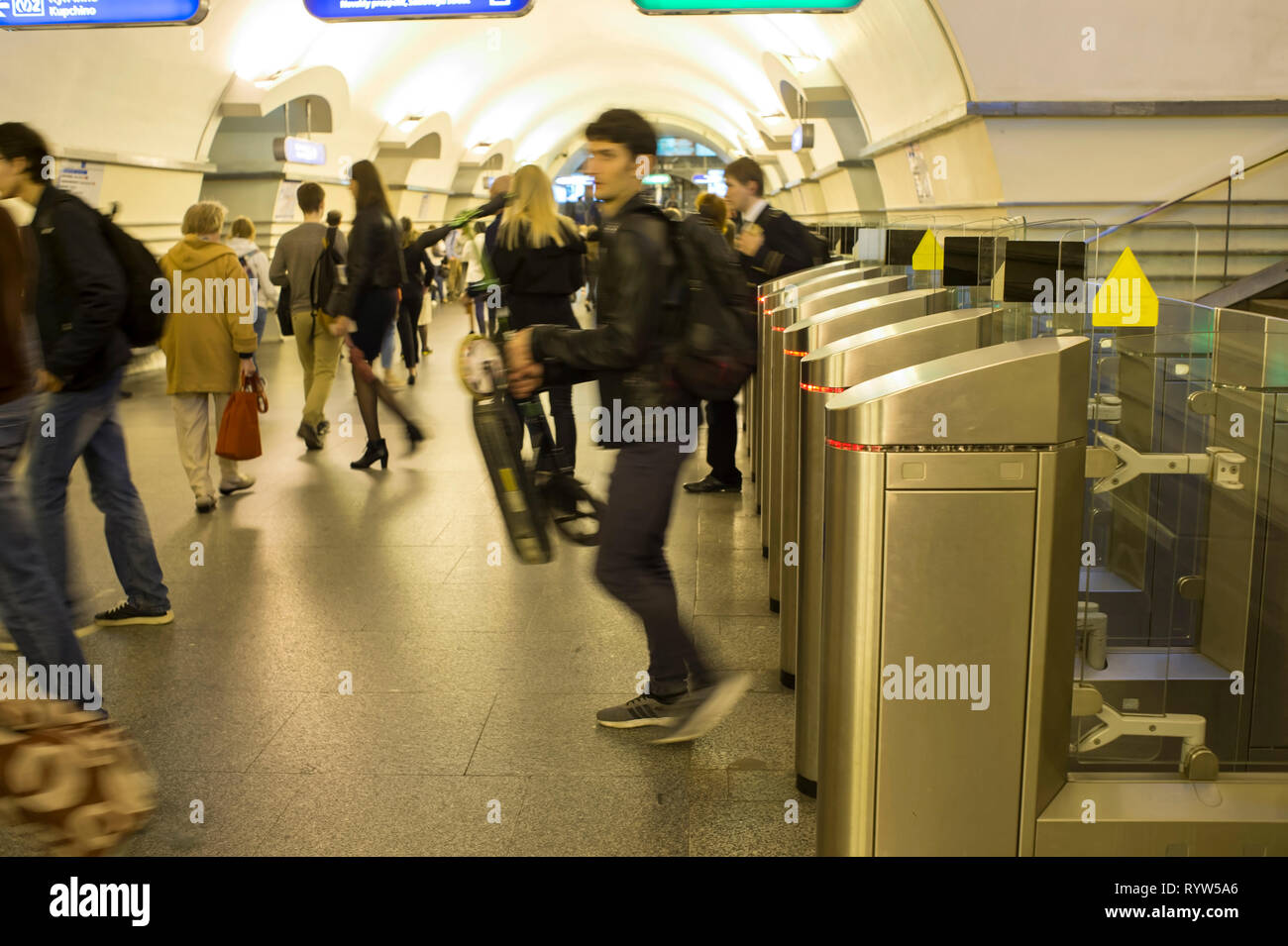Blur. A crowd of people in a hurry passes through electronic turnstiles ...