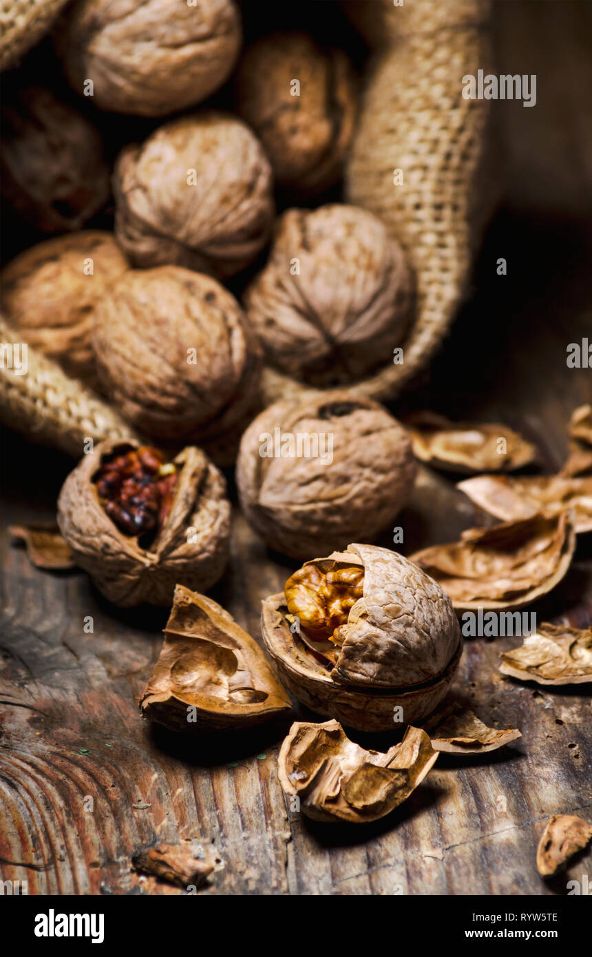Still life with walnuts and cracked shells in vintage burlap bag. Whole ...