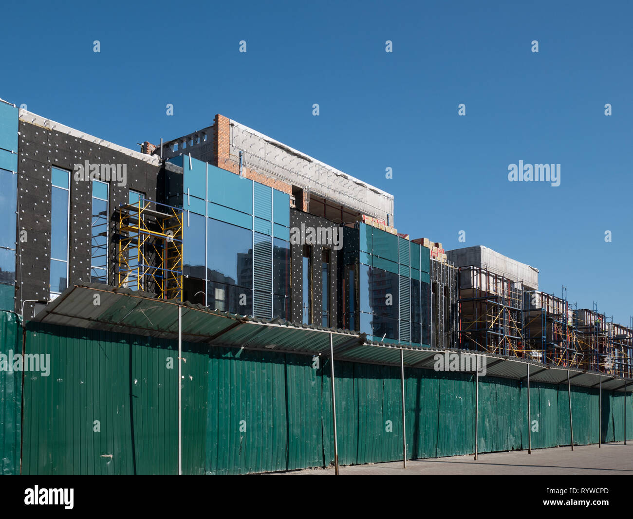 long green wooden fence at construction site. building small shopping ...