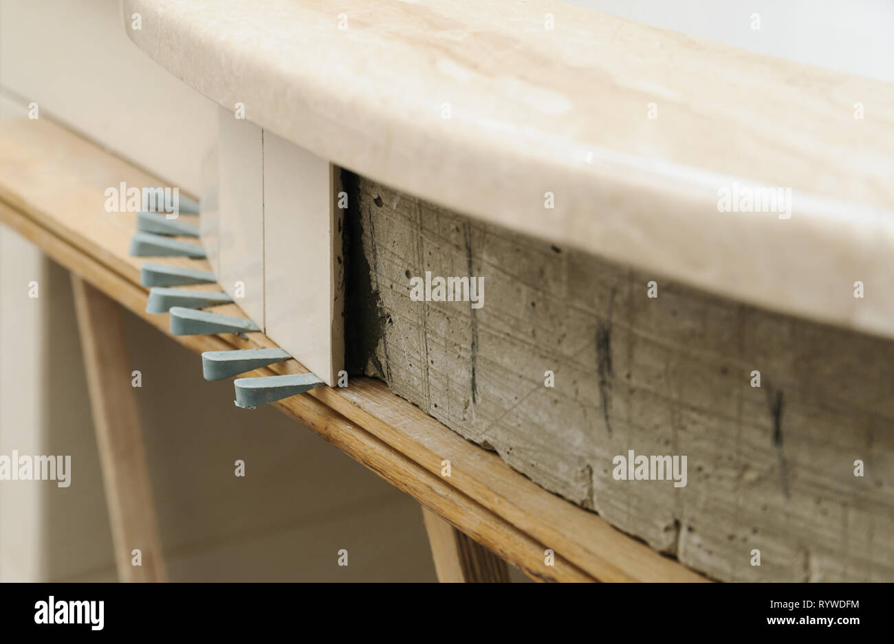 Ceramic tiles installed on the curved wall and propped with plastic ...