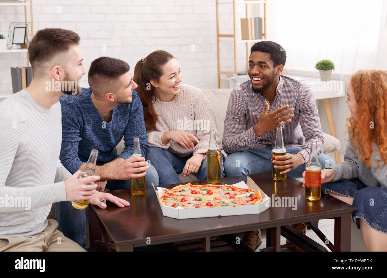 Happy friends eating pizza and talking at home Stock Photo - Alamy